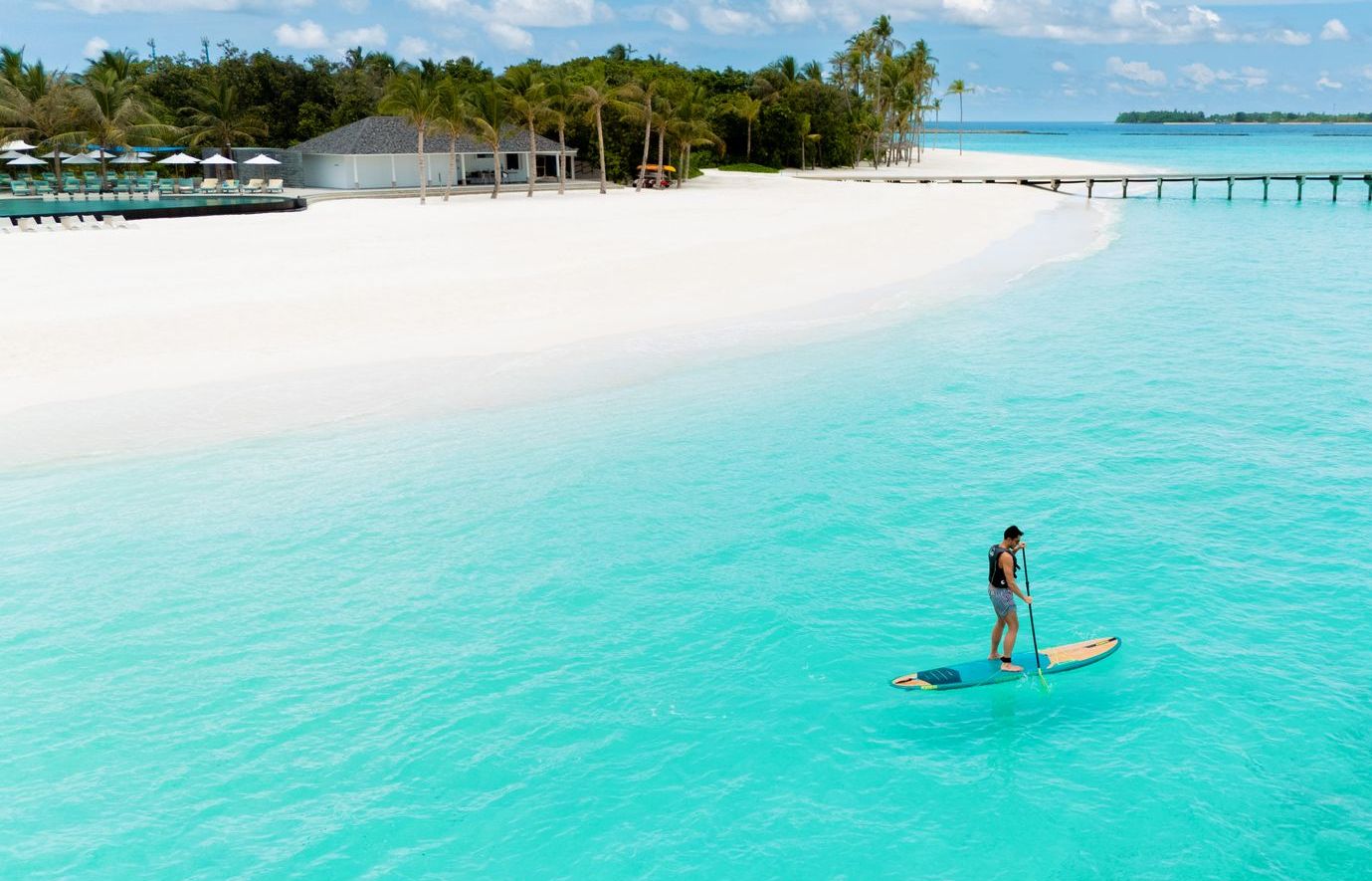 Couple strolling on beach with paddle boards